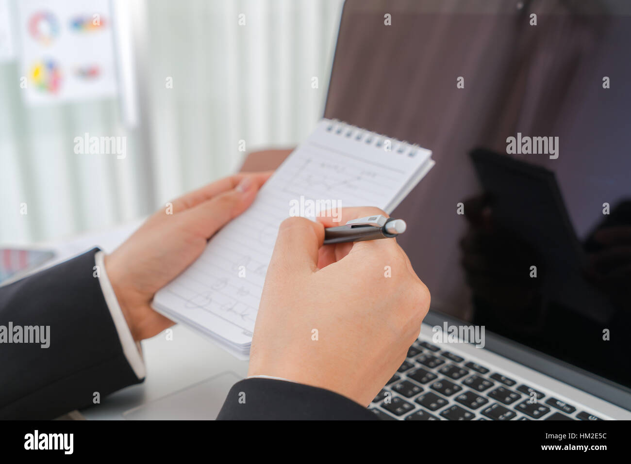 Business people using a pencil noting over laptop Stock Photo - Alamy