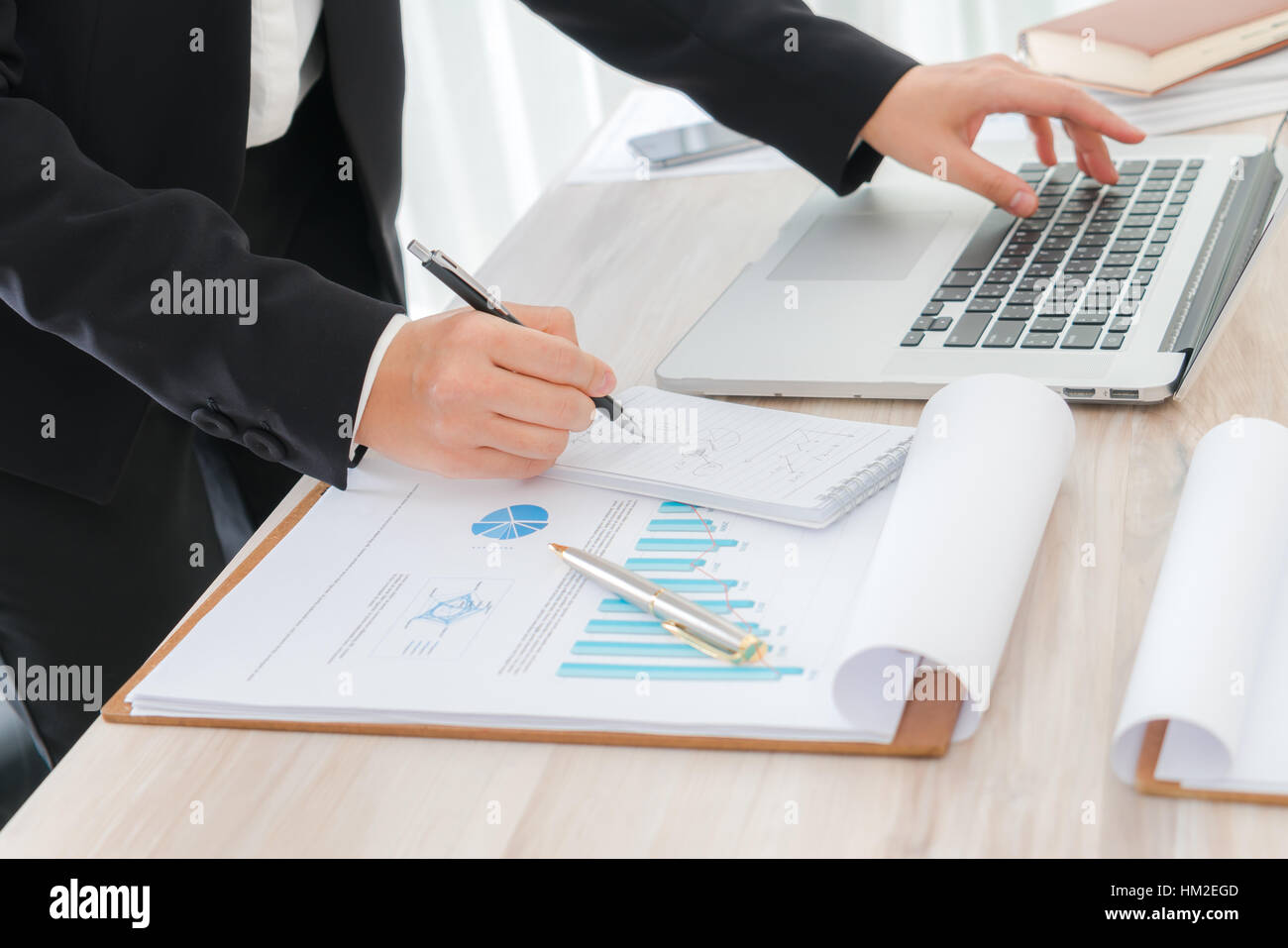 Business people using a pencil noting over laptop Stock Photo - Alamy