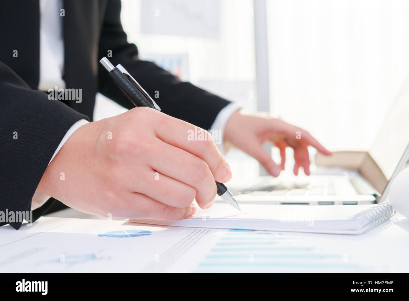Business people using a pencil noting over laptop Stock Photo - Alamy