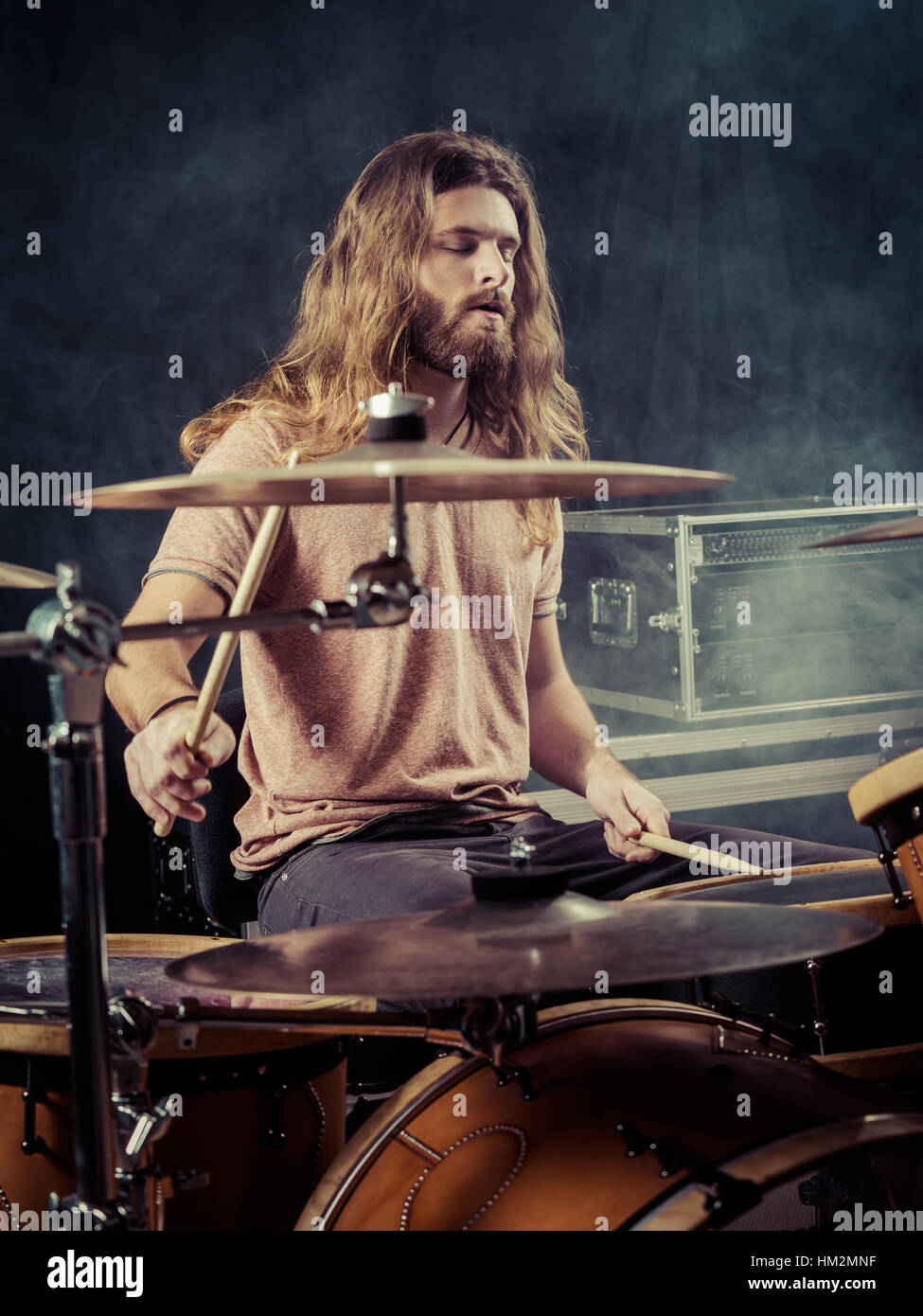 Photo of a young male drummer with long hair playing his drum set ...