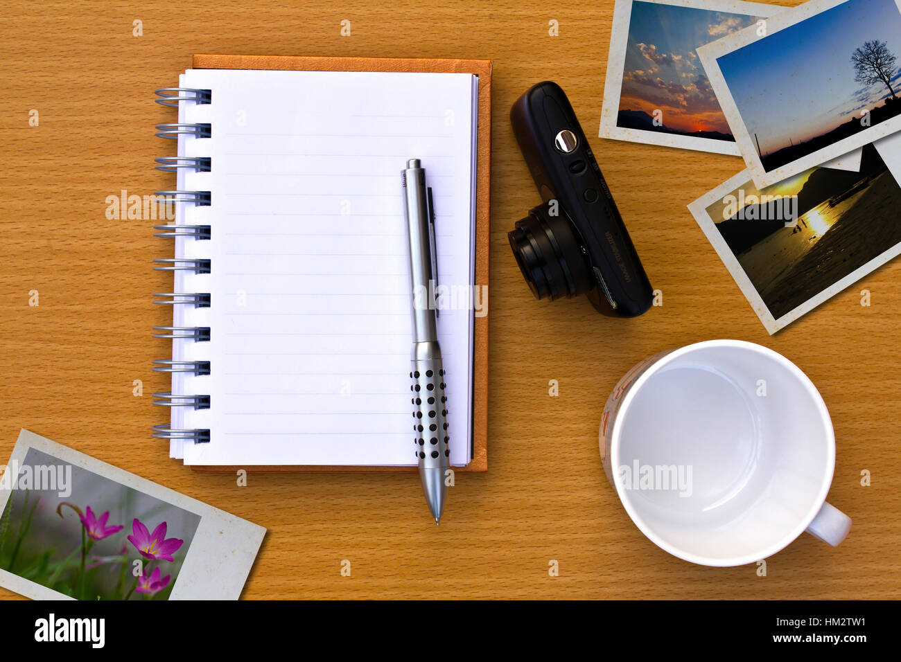 Note book , photo , pen and camera. On the floor of the wooden table ...