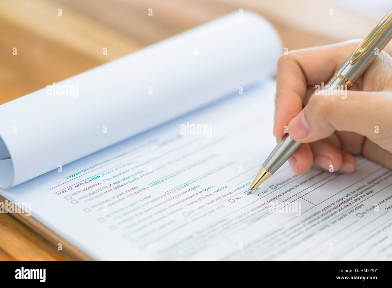 Hand with pen over application form Stock Photo - Alamy