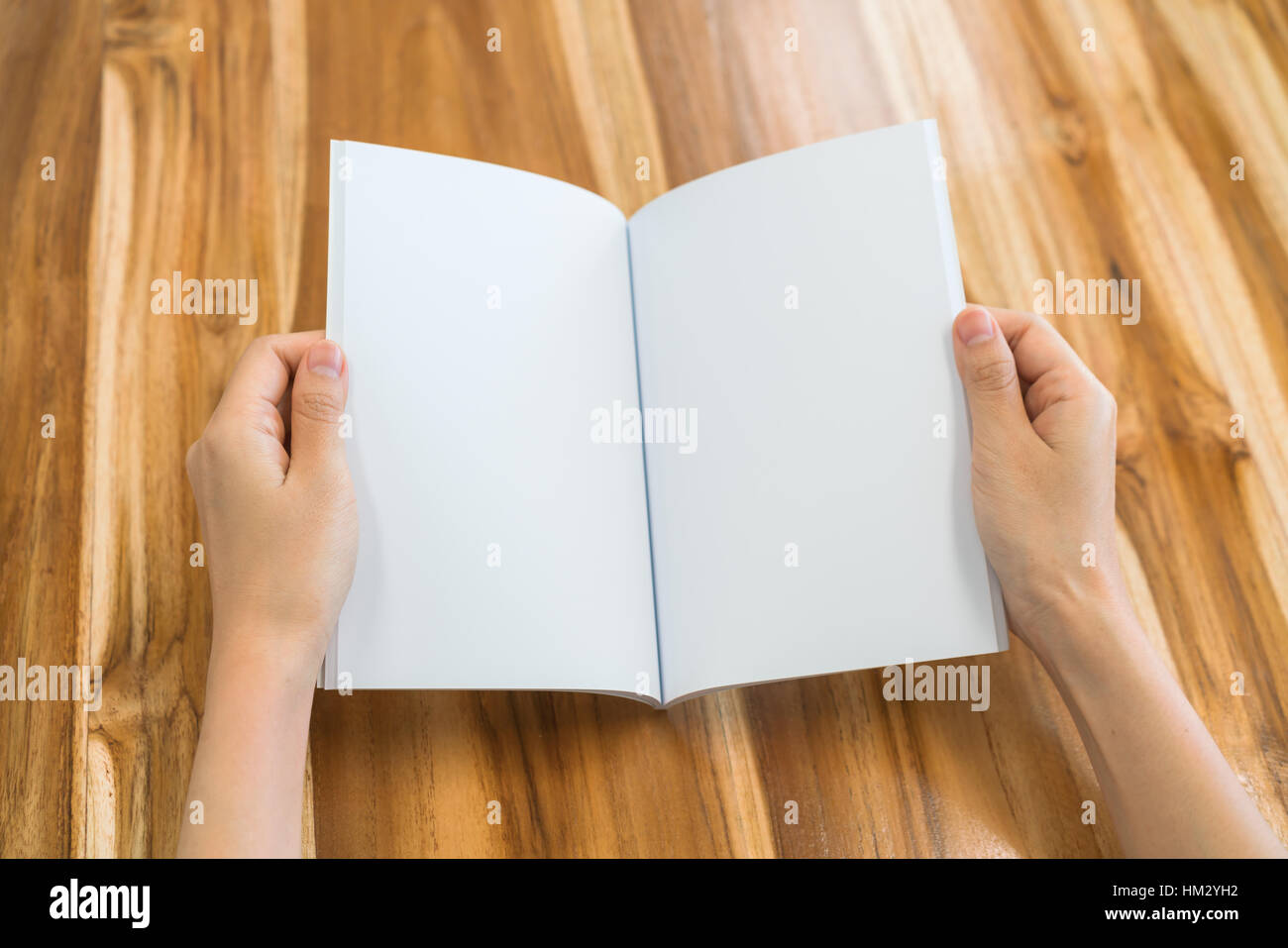 Hands open book on wood table Stock Photo - Alamy