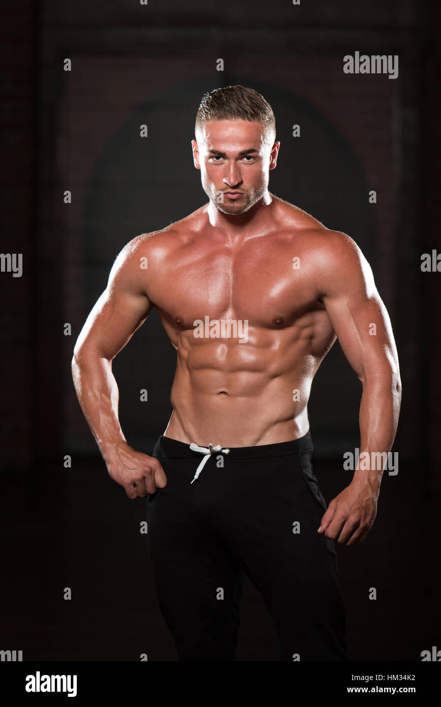 Healthy Young Man Standing Strong In The Gym And Flexing Muscles ...