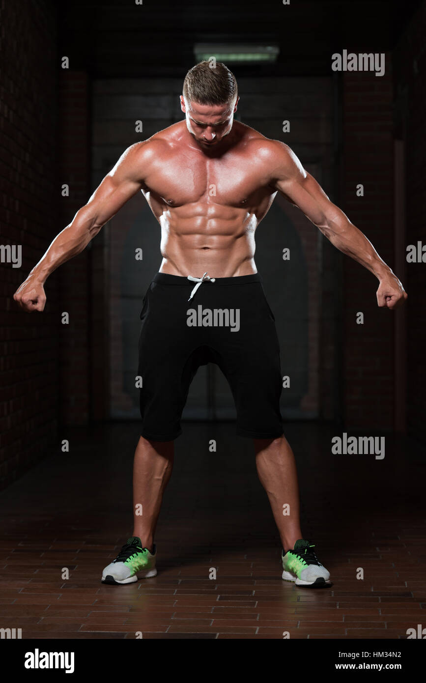 Healthy Young Man Standing Strong In The Gym And Flexing Muscles ...