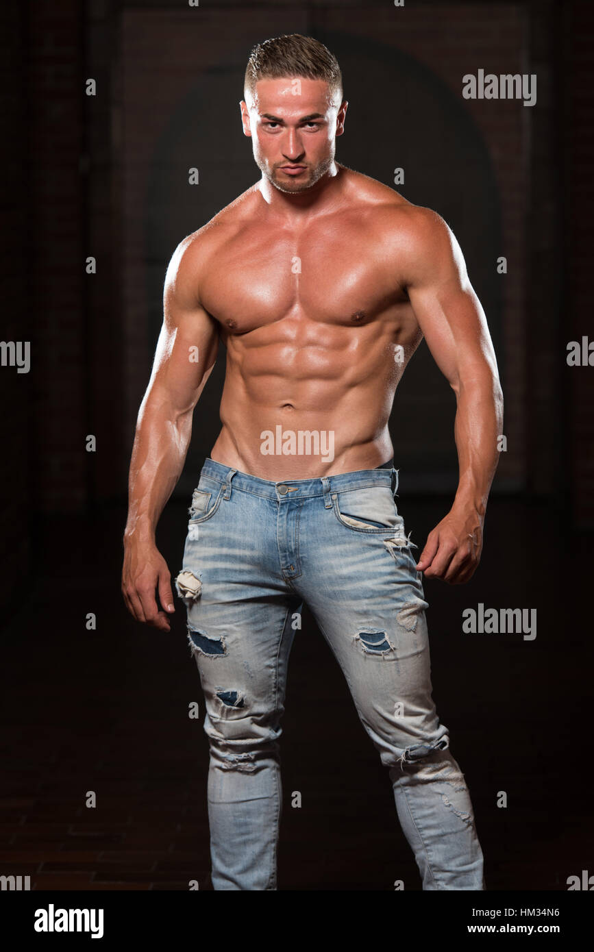Healthy Young Man In Jeans Standing Strong In The Gym And Flexing ...