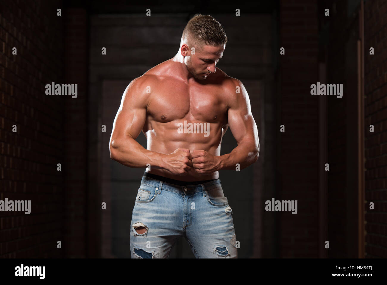 Handsome Young Man In Jeans Standing Strong In The Gym And Flexing ...