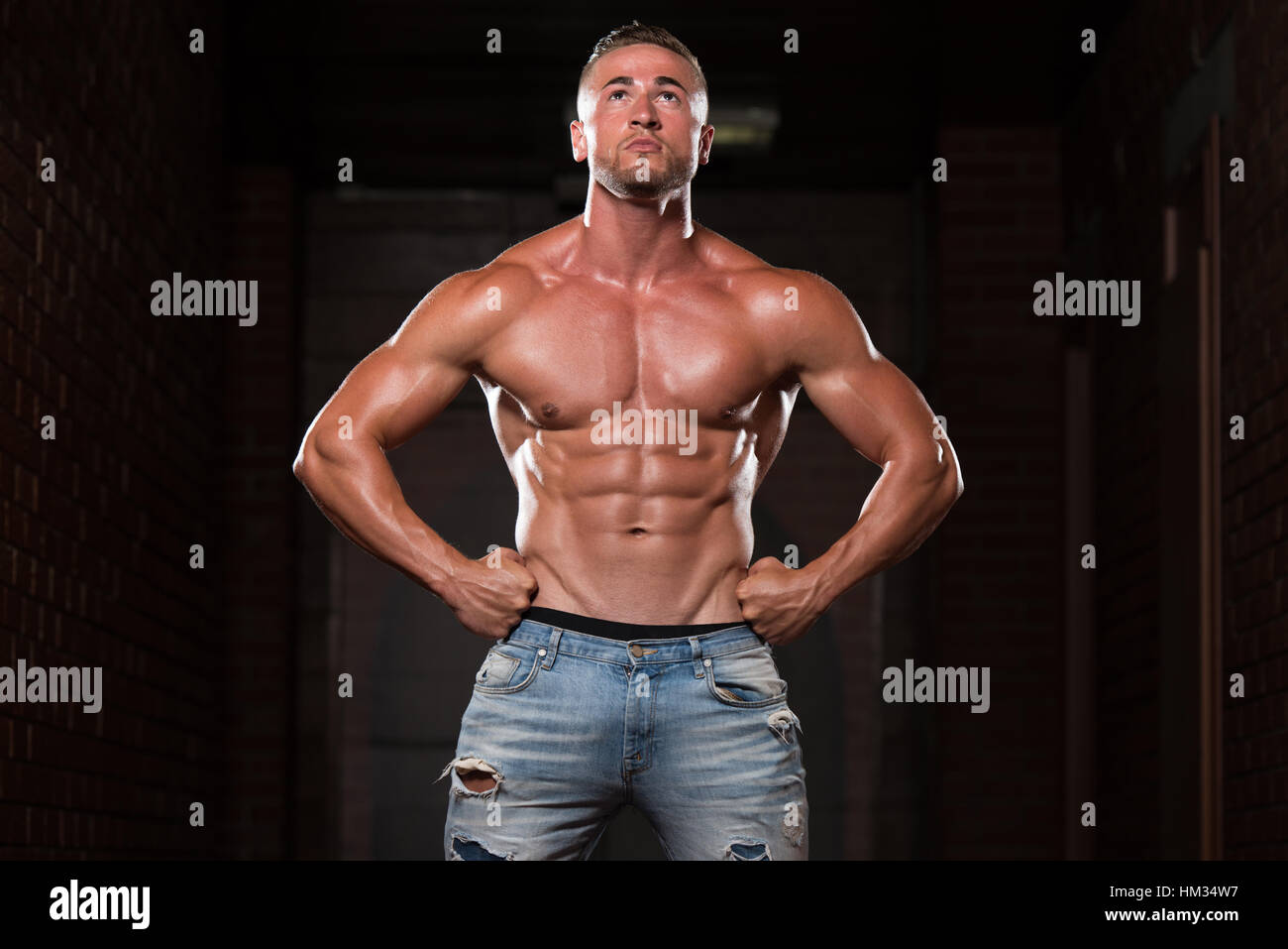 Healthy Young Man In Jeans Standing Strong In The Gym And Flexing ...