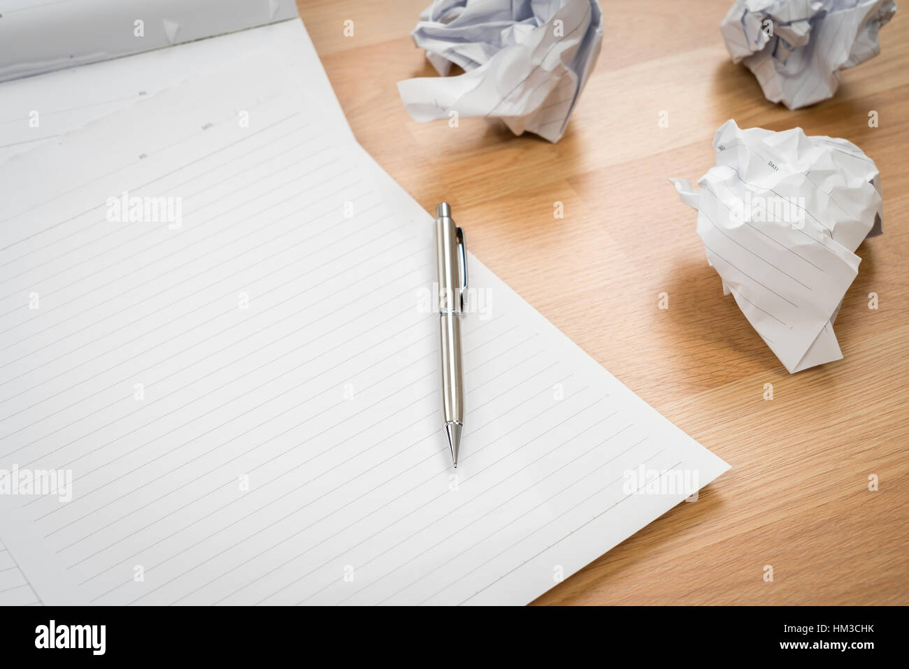 White note book paper with pencil and crumpled paper on a wooden desk ...