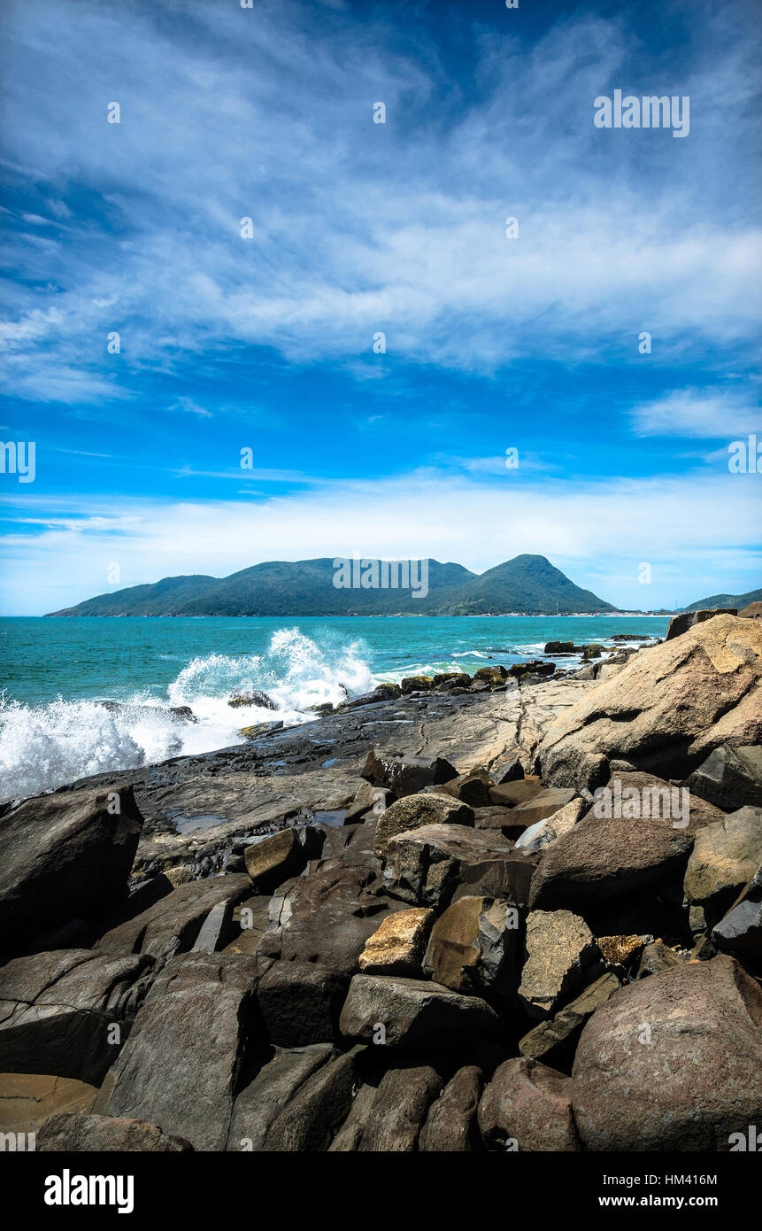 Coast full of rocks, waves of sea water hitting the rocks, blue sea and ...