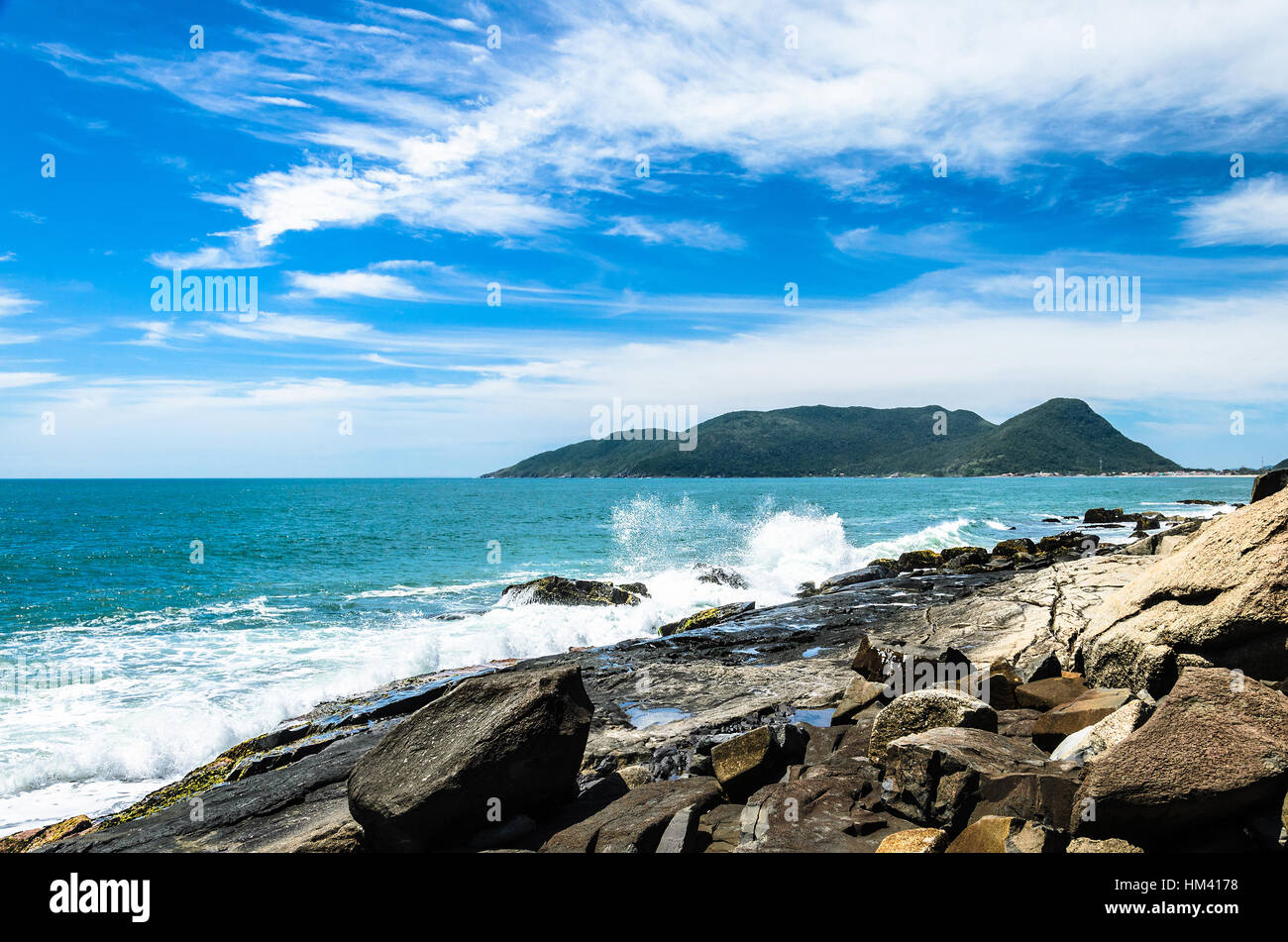 Coast full of rocks, waves of sea water hitting the rocks, blue sea and ...