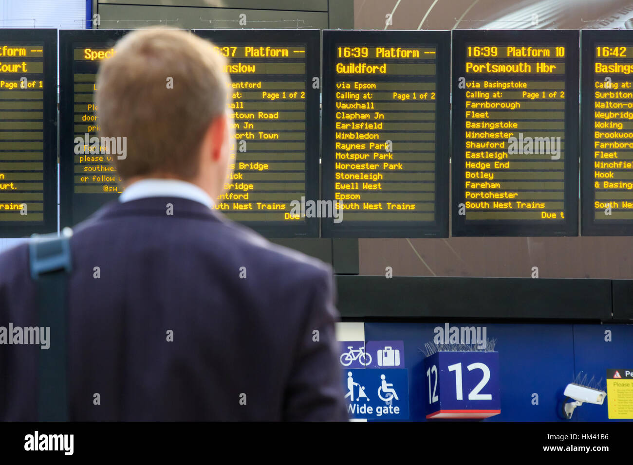 Commuter checking timetables at a train station Stock Photo - Alamy