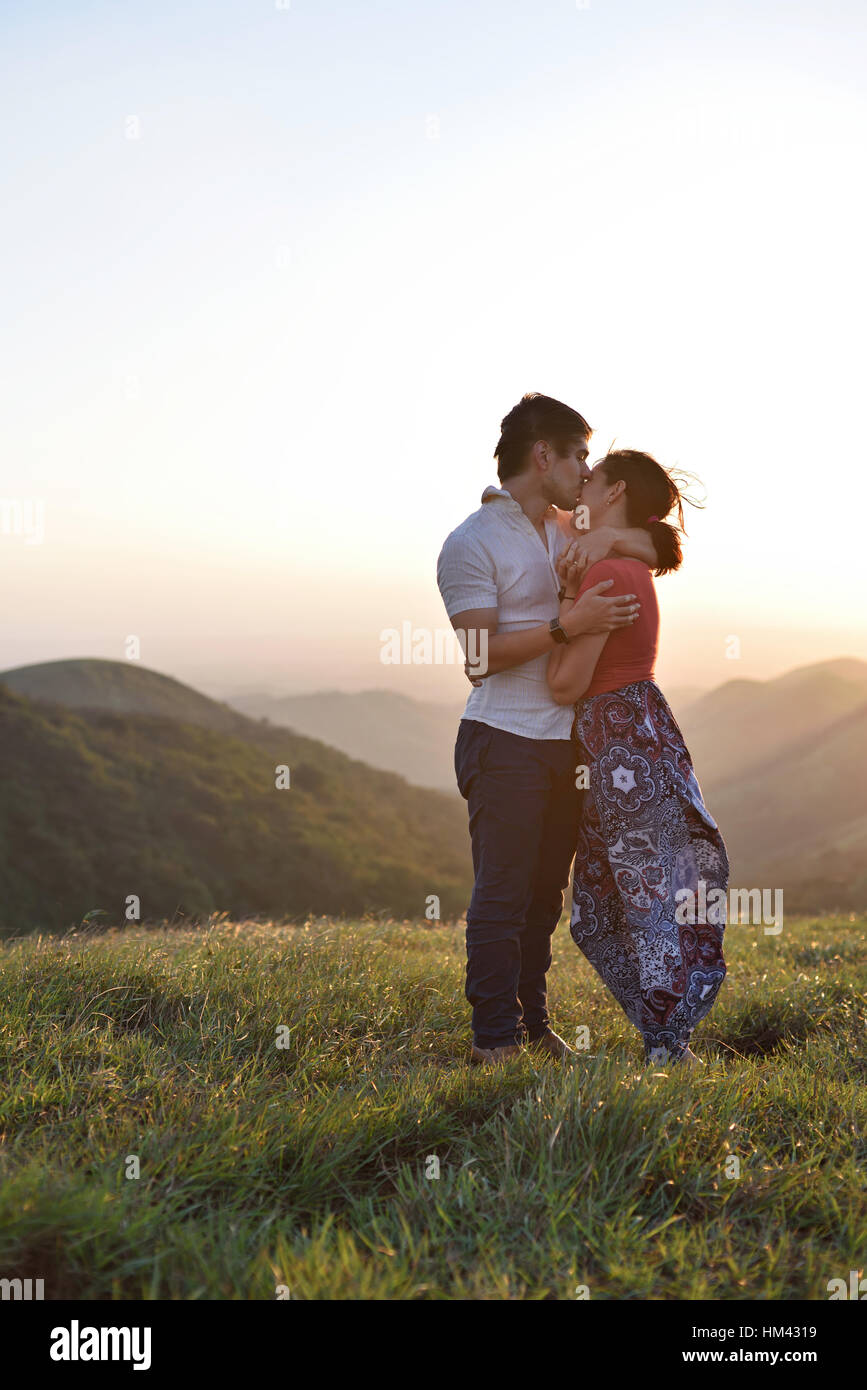 couple hugging stand in gold grass during sunset Stock Photo - Alamy