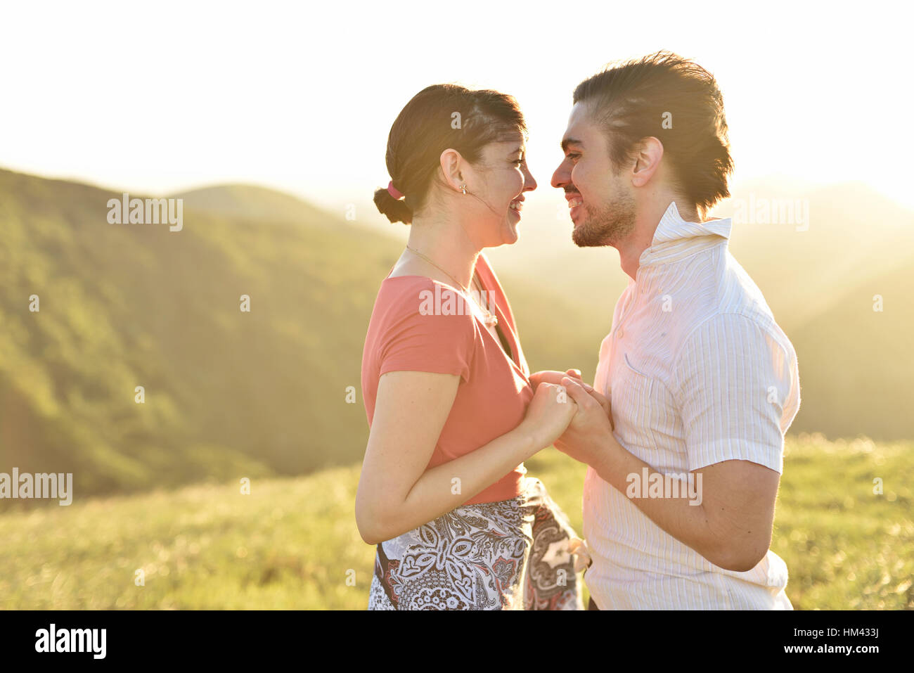 Man and woman smile holding hands on sunny light Stock Photo - Alamy