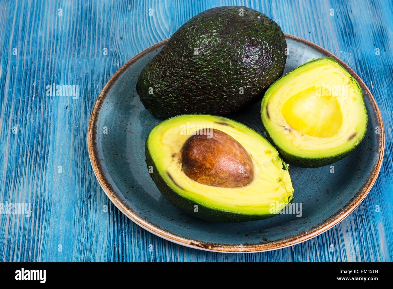 Sliced avocado with stone on blue background Stock Photo - Alamy