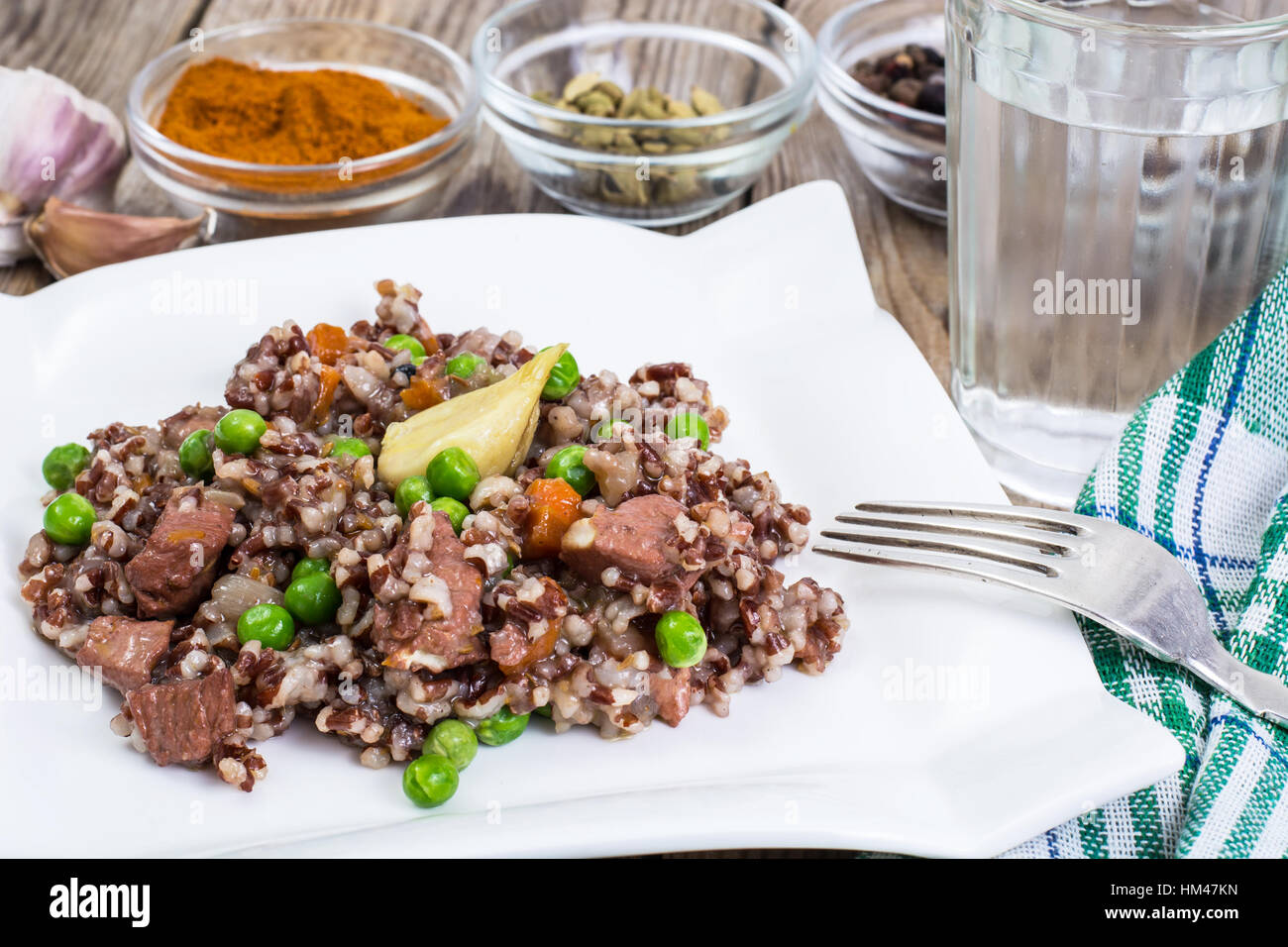 Boiled red rice with vegetables and slices of chicken on a woode Stock ...