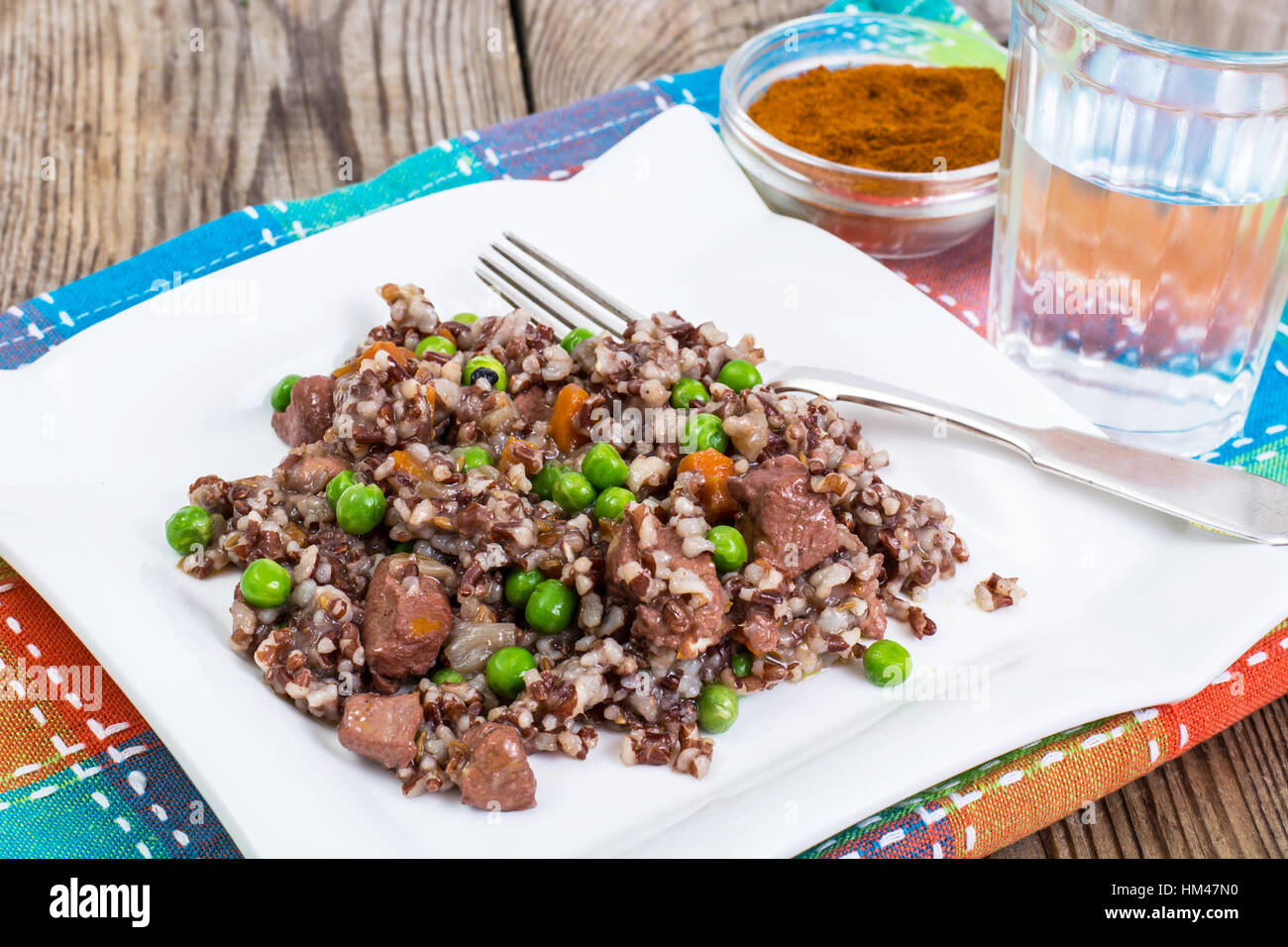 Boiled red rice with vegetables and slices of chicken on a woode Stock ...