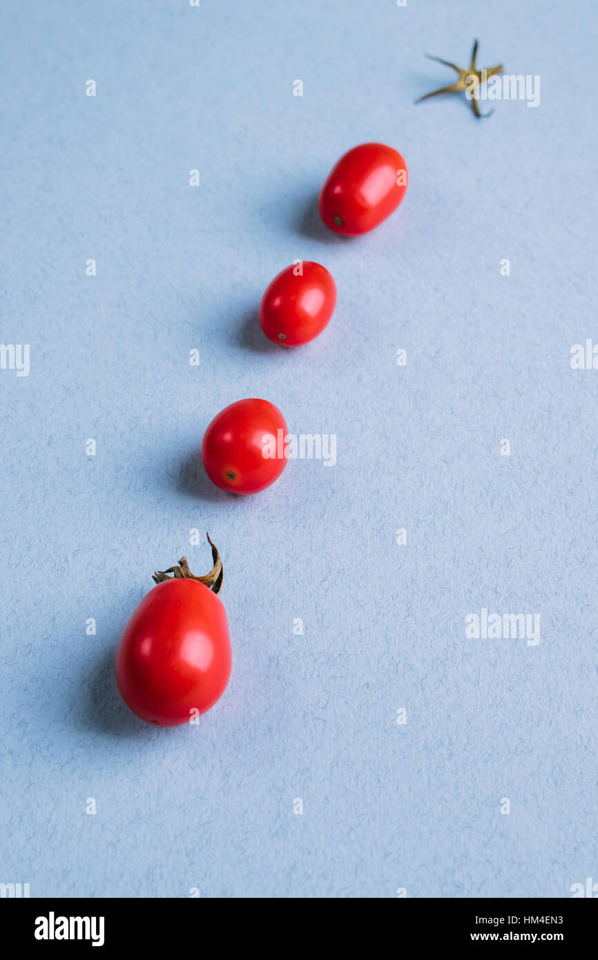 Four red tomatoes on a blue table, top view Stock Photo - Alamy