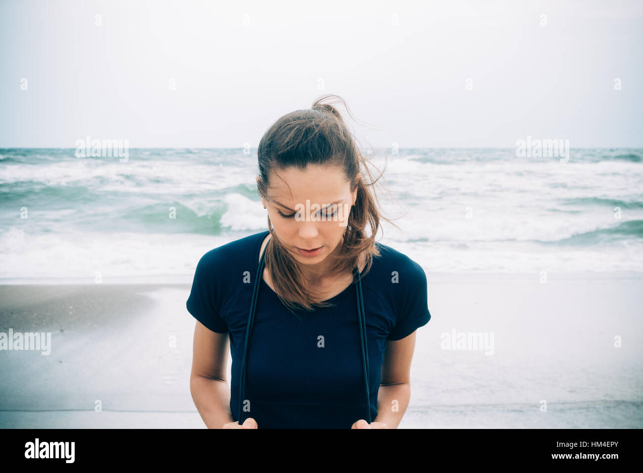 Attractive female athlete with a skipping rope on the beach in cold ...