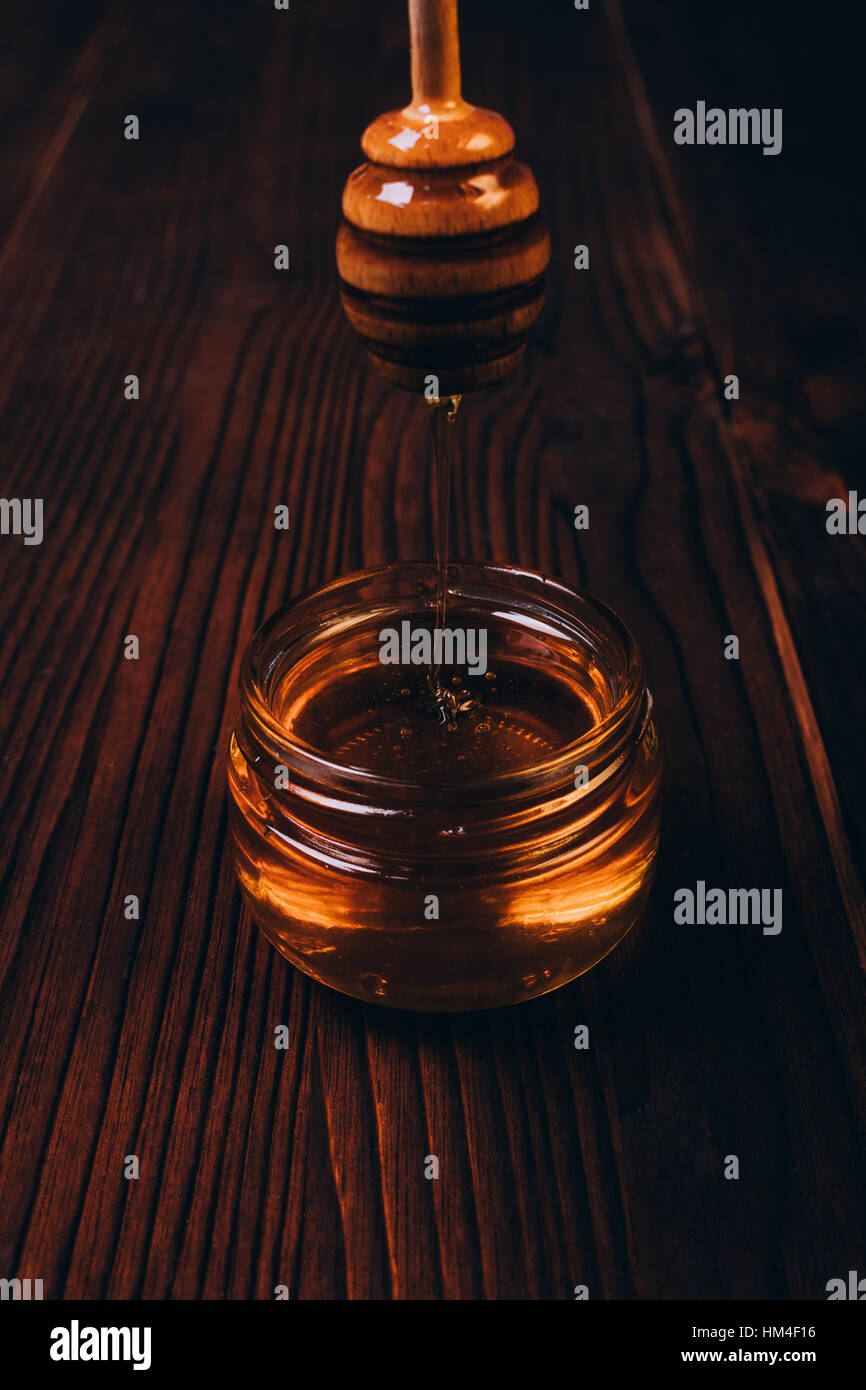 Vertical frame Honey dripping into jar on a table close-up Stock Photo ...