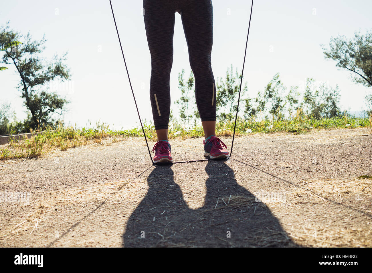 Female feet in running shoes and a skipping rope in the summer outdoors ...
