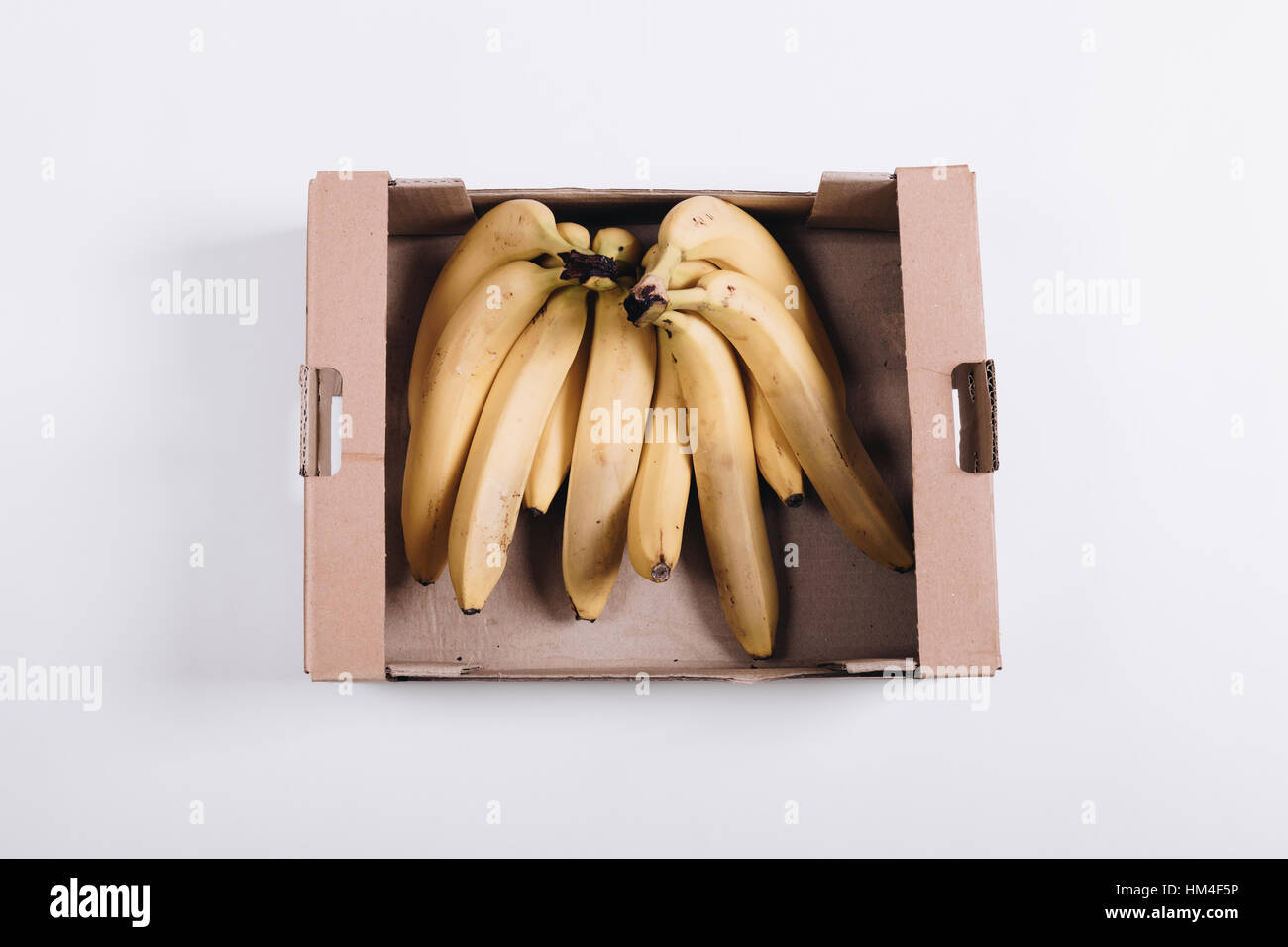 Bunch of bananas in a cardboard box on a white background, top view ...