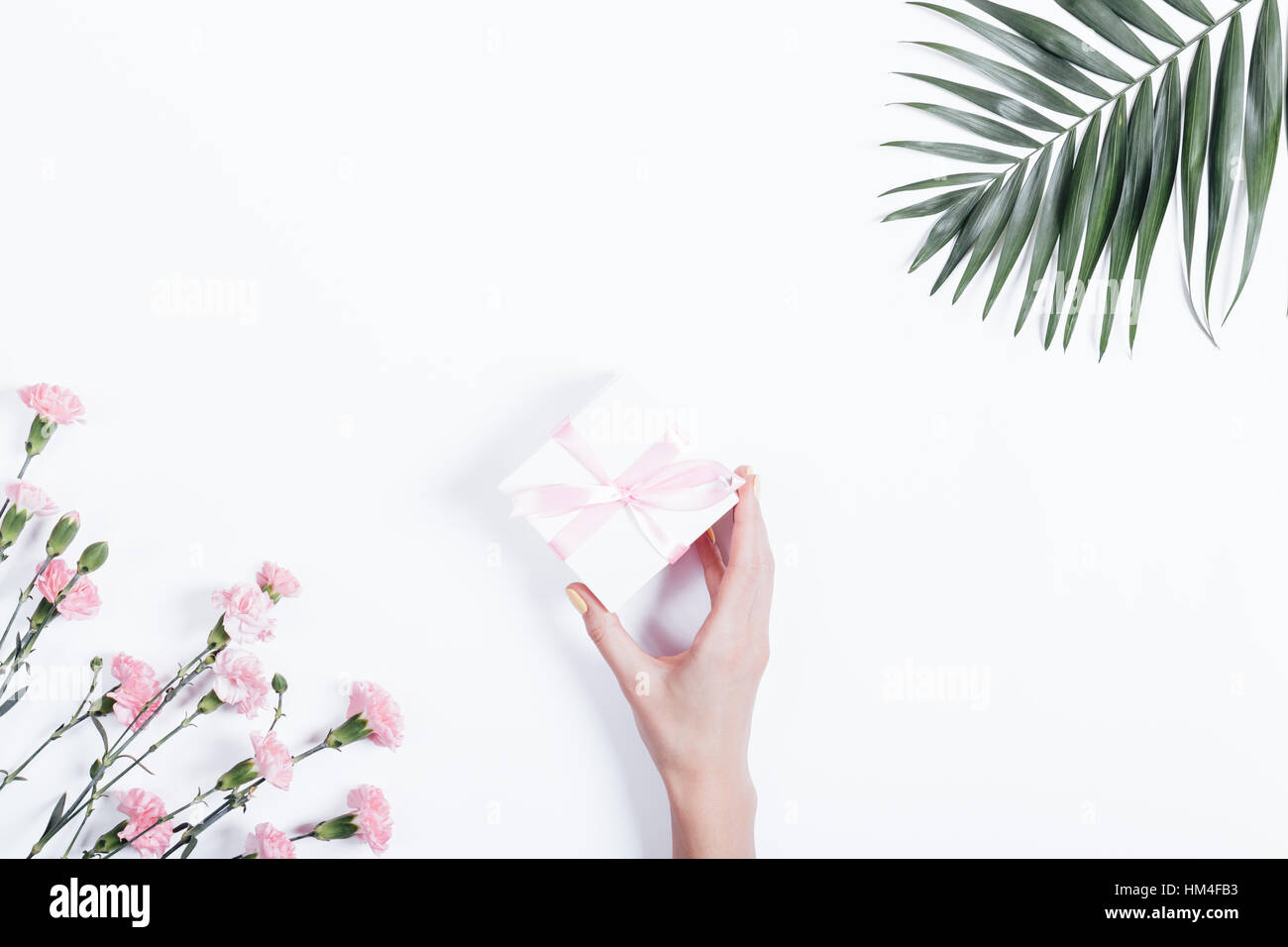 Holiday concept: female hand puts on the white table box gift. Top view ...