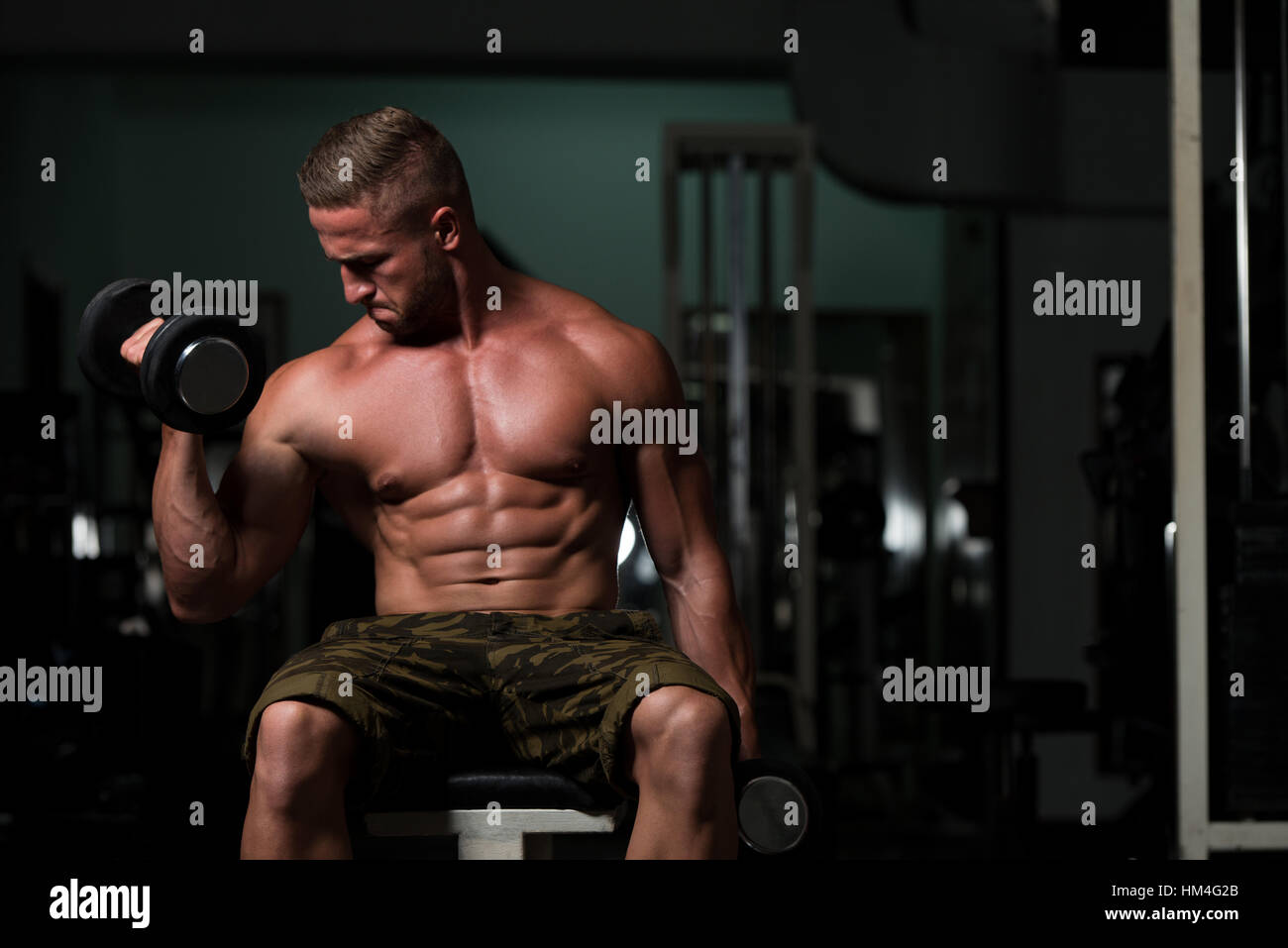 Healthy Man Working Out Biceps In A Dark Gym - Dumbbell Concentration ...