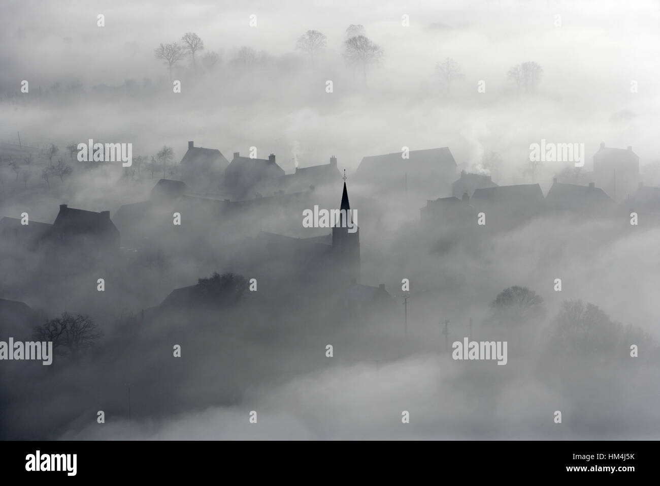 Village of Saint-Pierre-d'Entremont (north-western France) in the mist ...