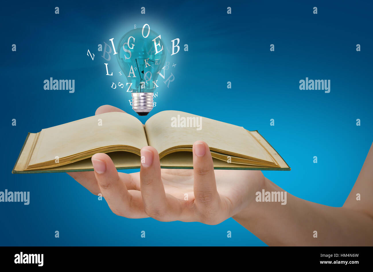 Book and light bulb on hand Stock Photo - Alamy