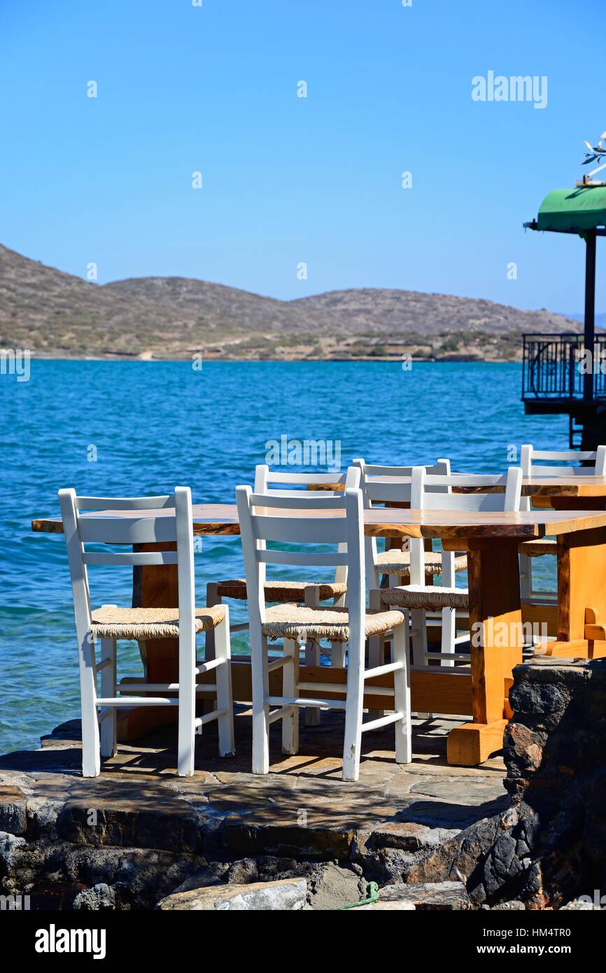 Restaurant tables on the waterfront with views across the bay, Elounda ...
