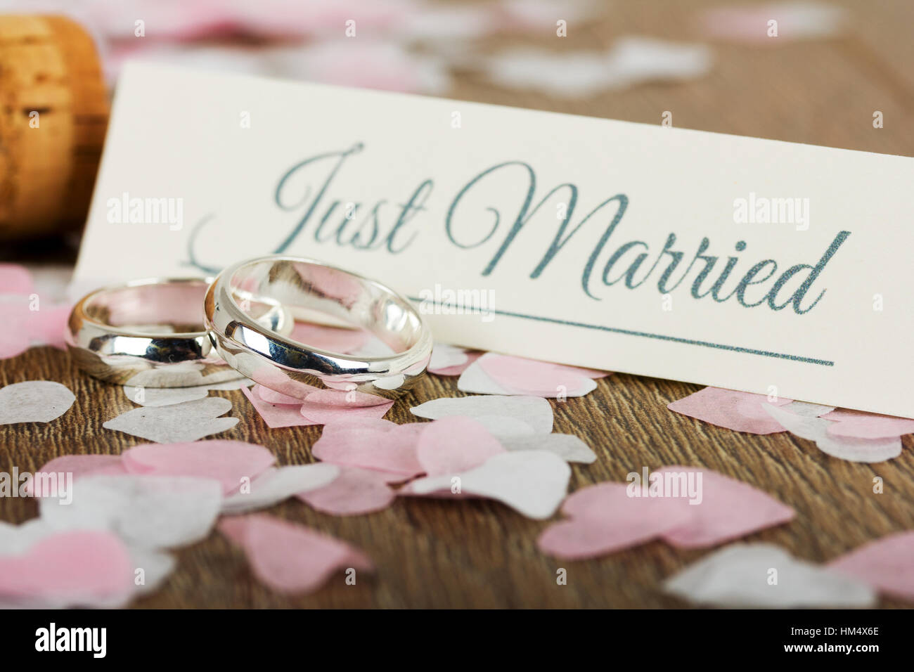 pair of white gold wedding rings on a wooden background with confetti ...