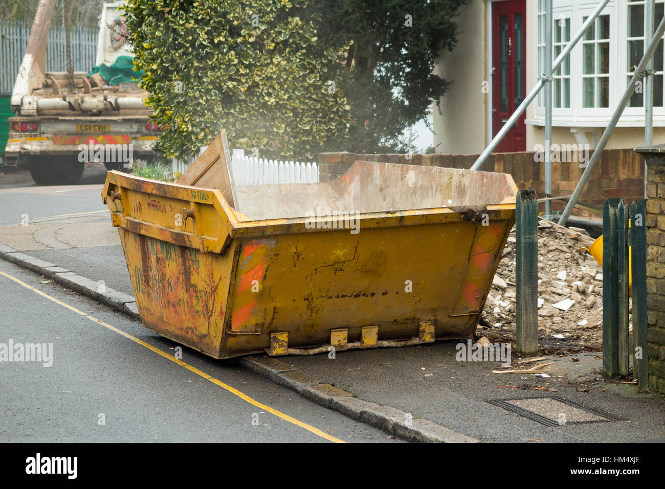 Builders waste rubbish skip, on pavement & yellow, line being filled ...