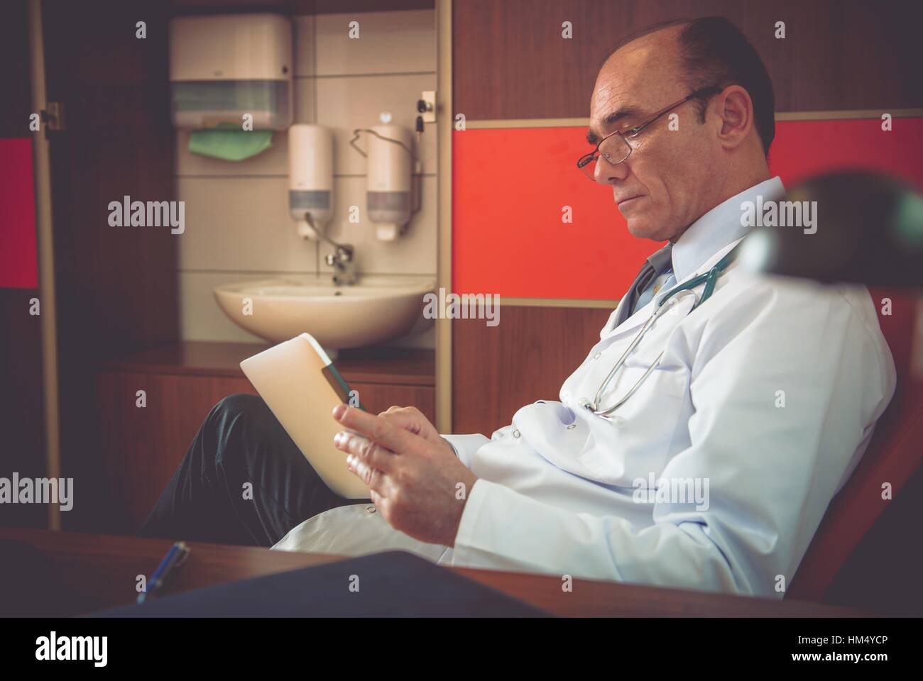 Senior Caucasian Medical Doctor in the Office Browsing Data on His ...