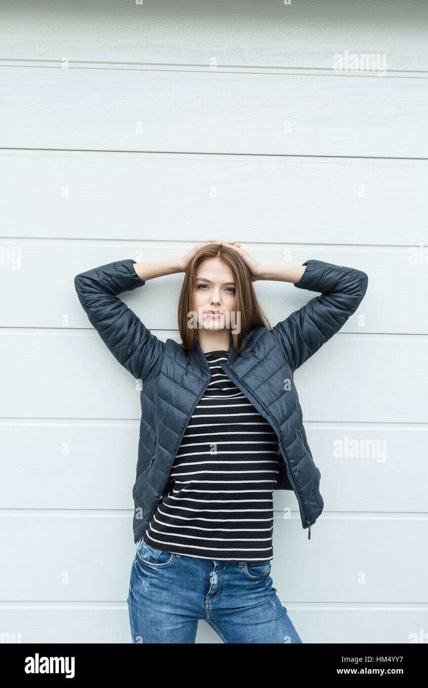 Portrait of young woman standing by wall Stock Photo - Alamy