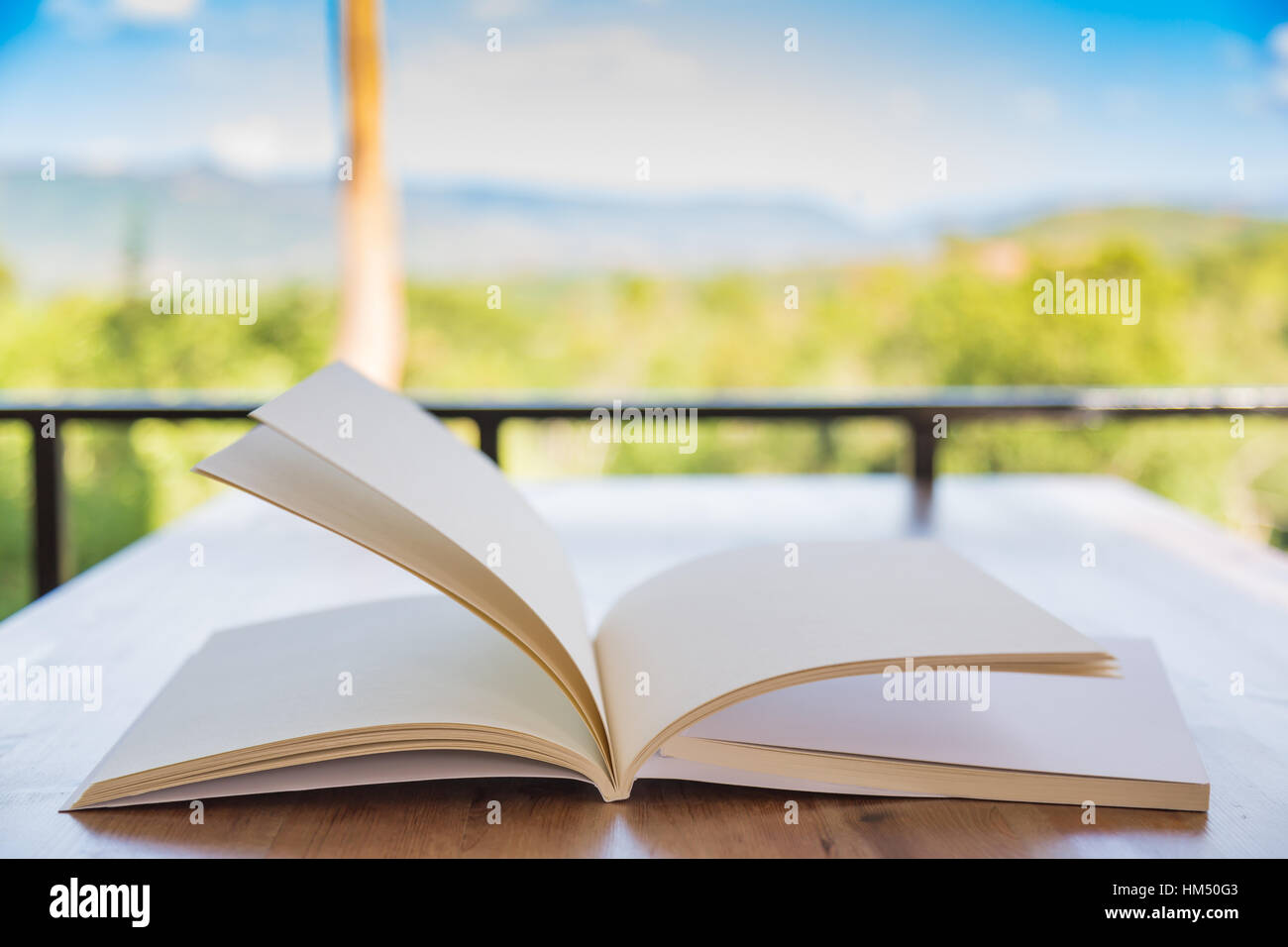 Open book on wood table in green forest ( moving page Stock Photo - Alamy