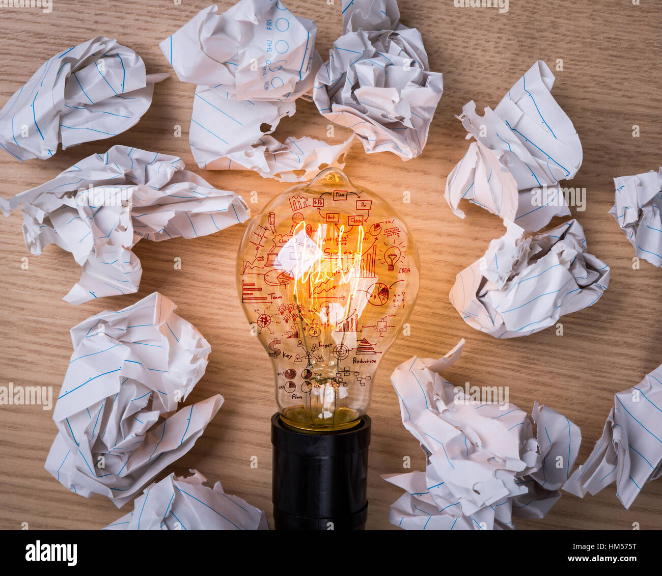 Light bulb and drawing graph inside with Crumpled paper on wood ...