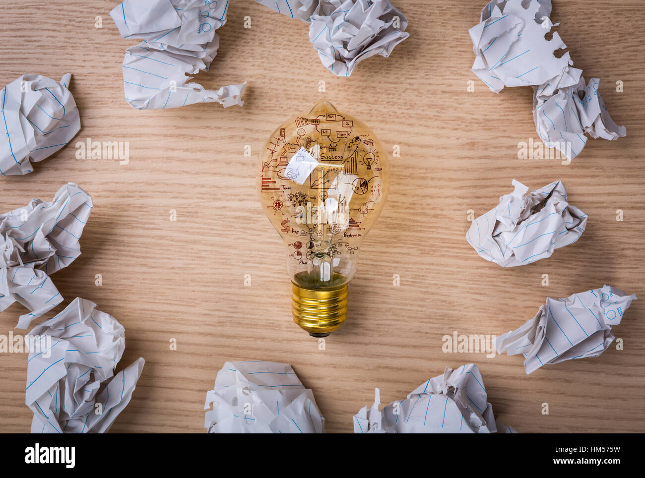 Light bulb and drawing graph inside with Crumpled paper on wood ...