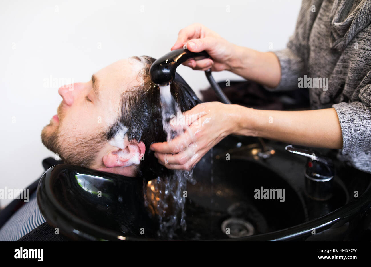 Professional hairdresser washing hair to her handsome client Stock ...