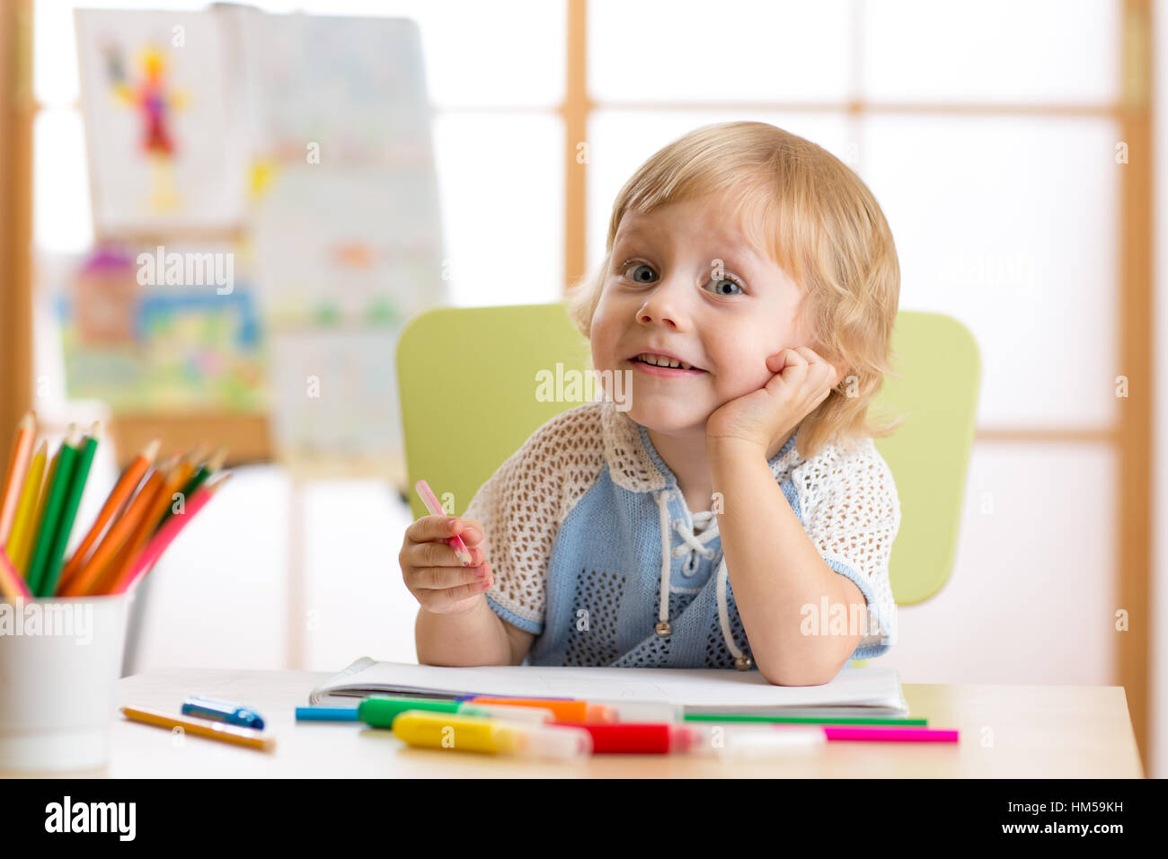 Smiling kid having an idea while drawing in nursery room Stock Photo ...