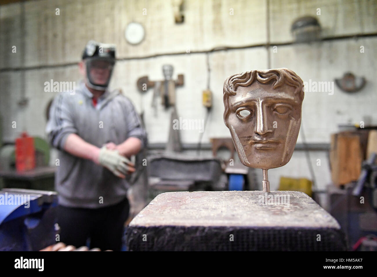 A bronze metal statue is filed down as it is made into a BAFTA mask at ...