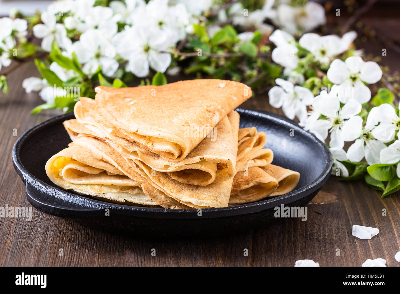 Homemade crepes folded in triangles on frying pan on spring blossom ...