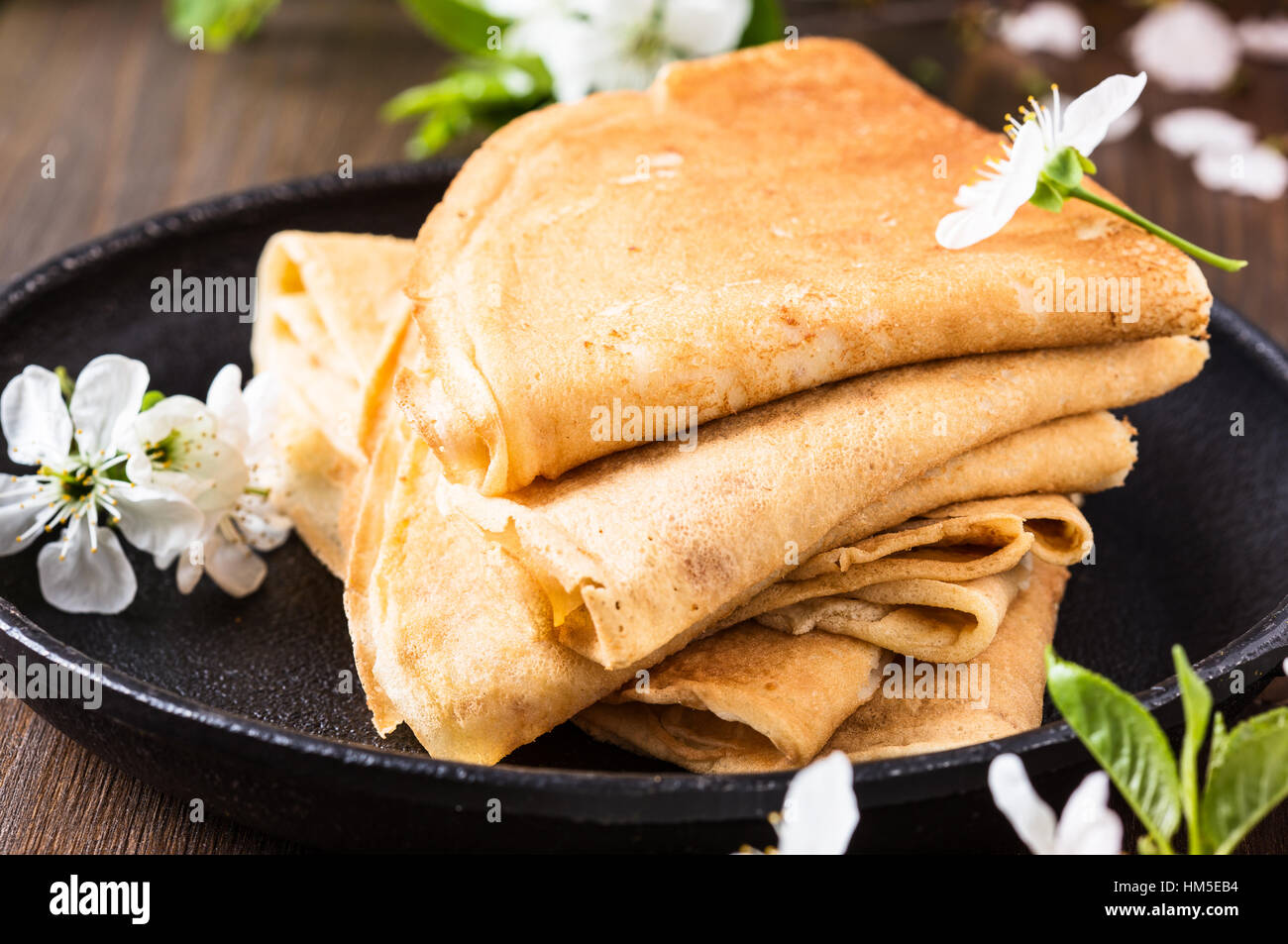Homemade crepes folded in triangles on frying pan on spring blossom ...
