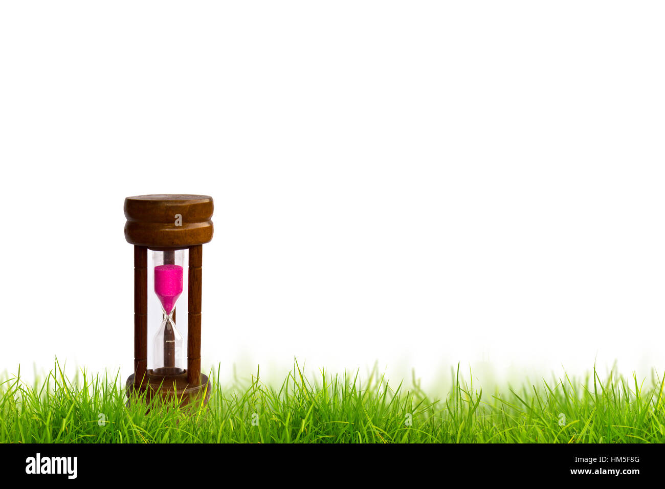 Sand clock in Fresh spring green grass panorama isolated on white ...