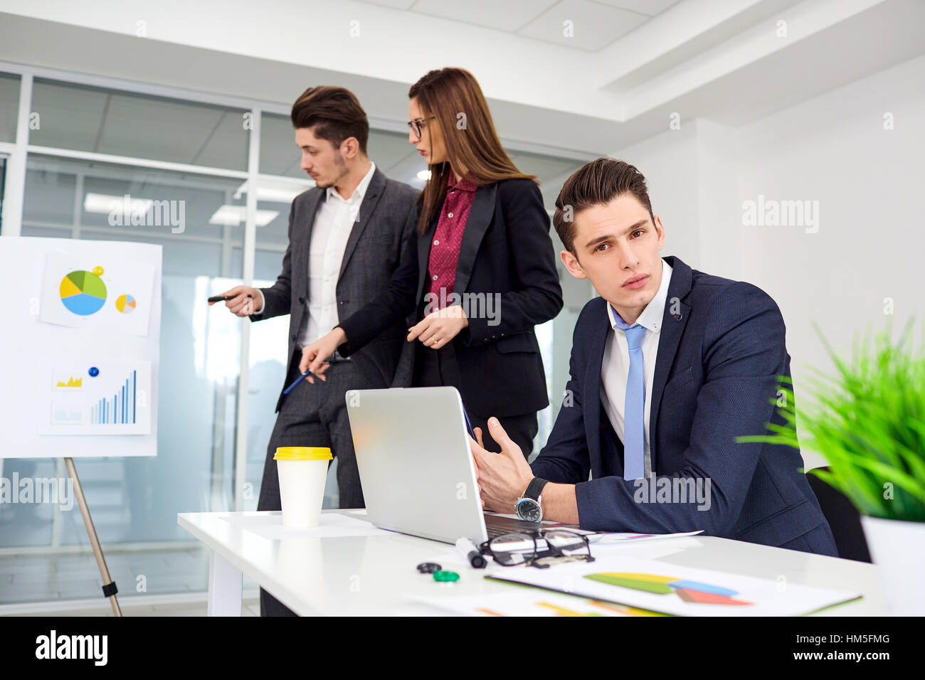 Young businessman at table on the background of his business partners ...