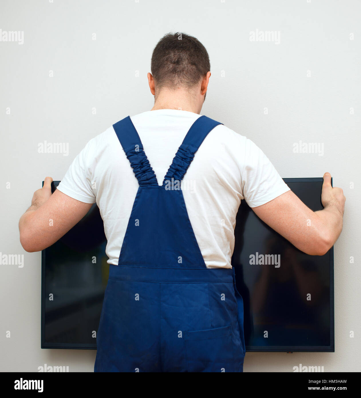 Man mounting TV on the wall Stock Photo - Alamy