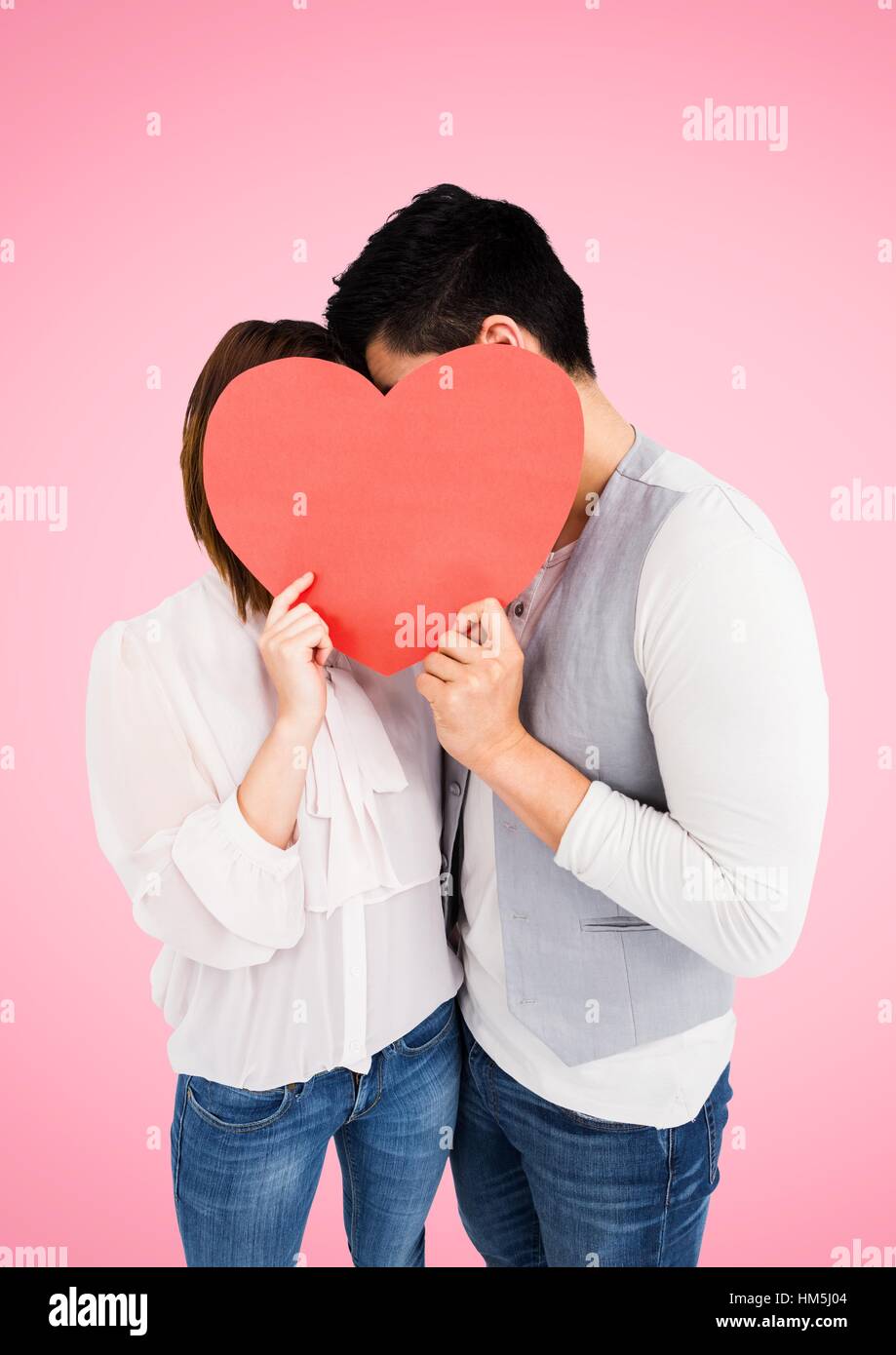 Couple hiding their face behind red heart Stock Photo - Alamy