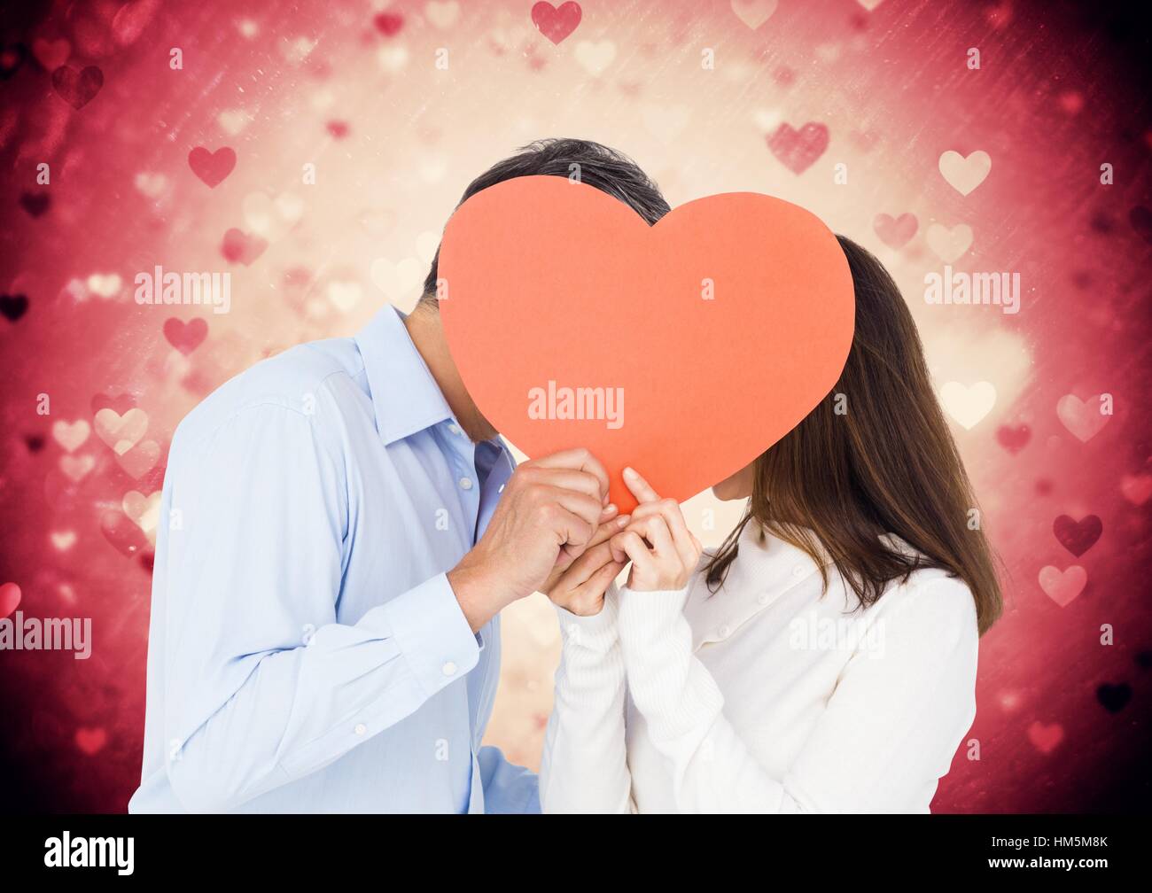 Romantic couple hiding their face behind heart Stock Photo - Alamy