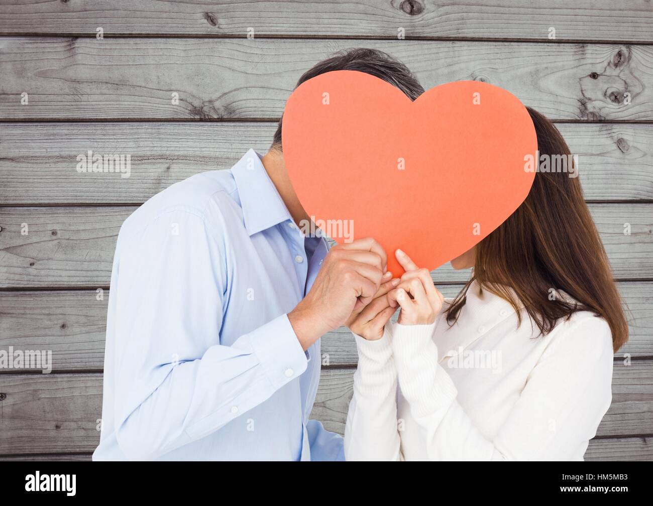 Romantic couple hiding their face behind heart Stock Photo - Alamy
