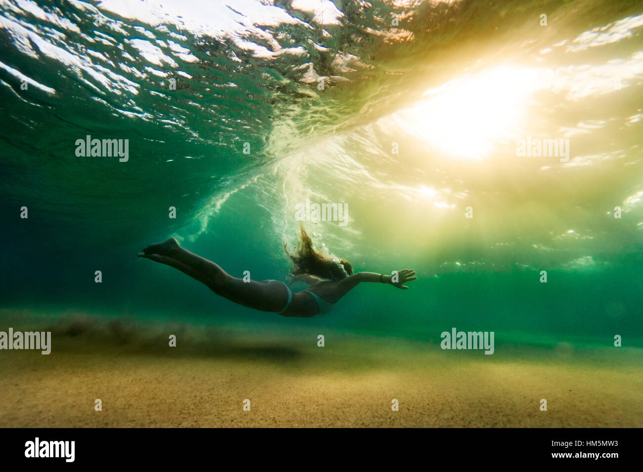 Side view of woman in bikini swimming underwater Stock Photo - Alamy